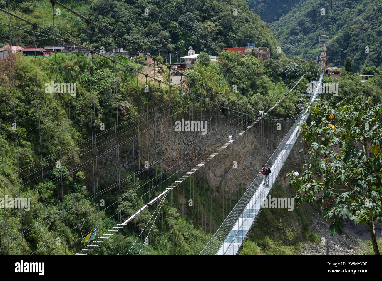 People walk on a long cable bridge over a deep gorge at an adventure ...