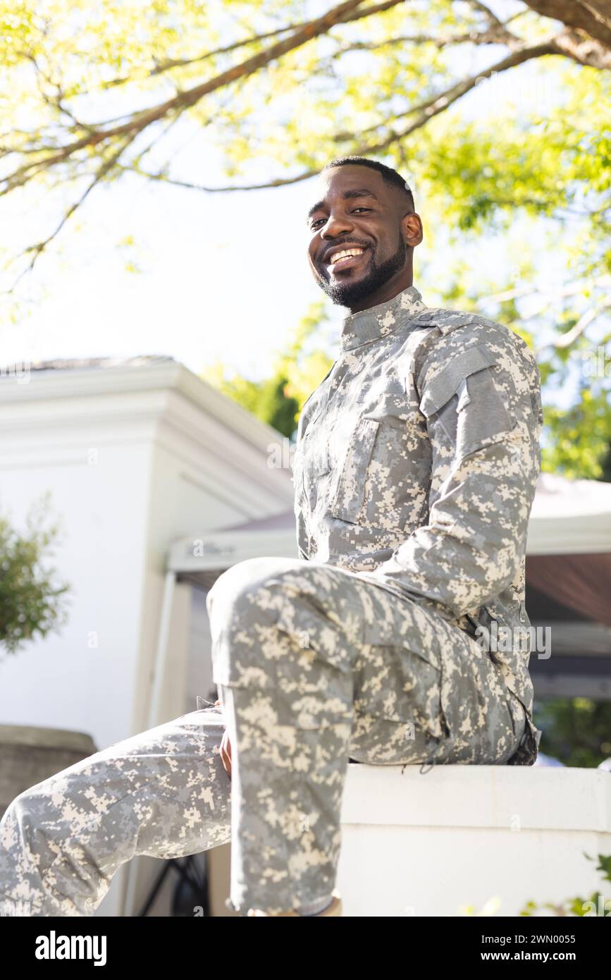 African American soldier in military uniform sits smiling under a tree ...