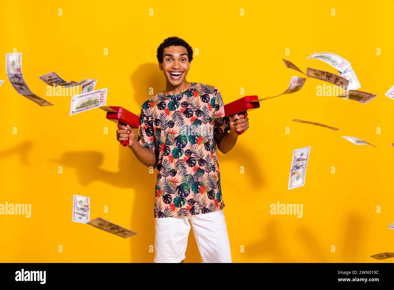 Photo of young crazy millionaire guy shooting money gun dollars ...