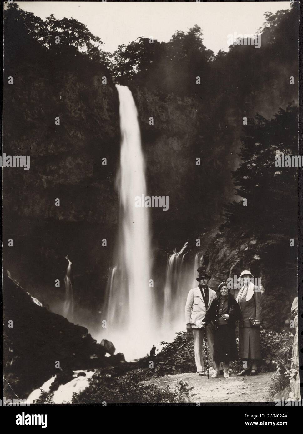 Three people standing in front of a waterfall. Three people standing in ...