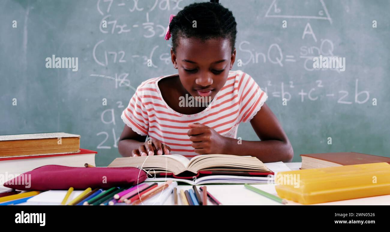 Image of mathematical equations floating over schoolchild sitting at ...