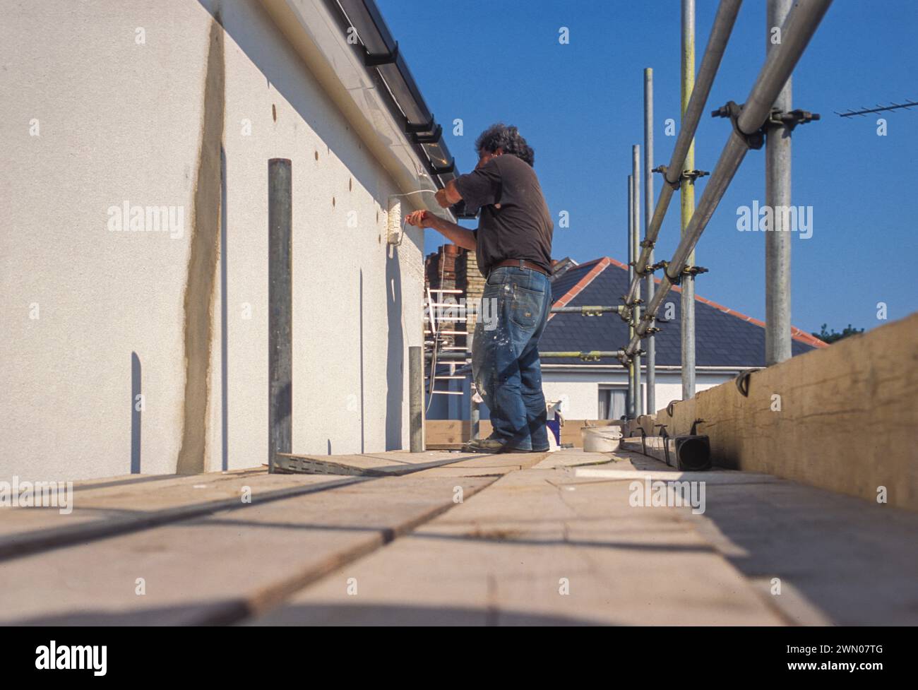 Workman fitting exterior wiring on a house Stock Photo - Alamy