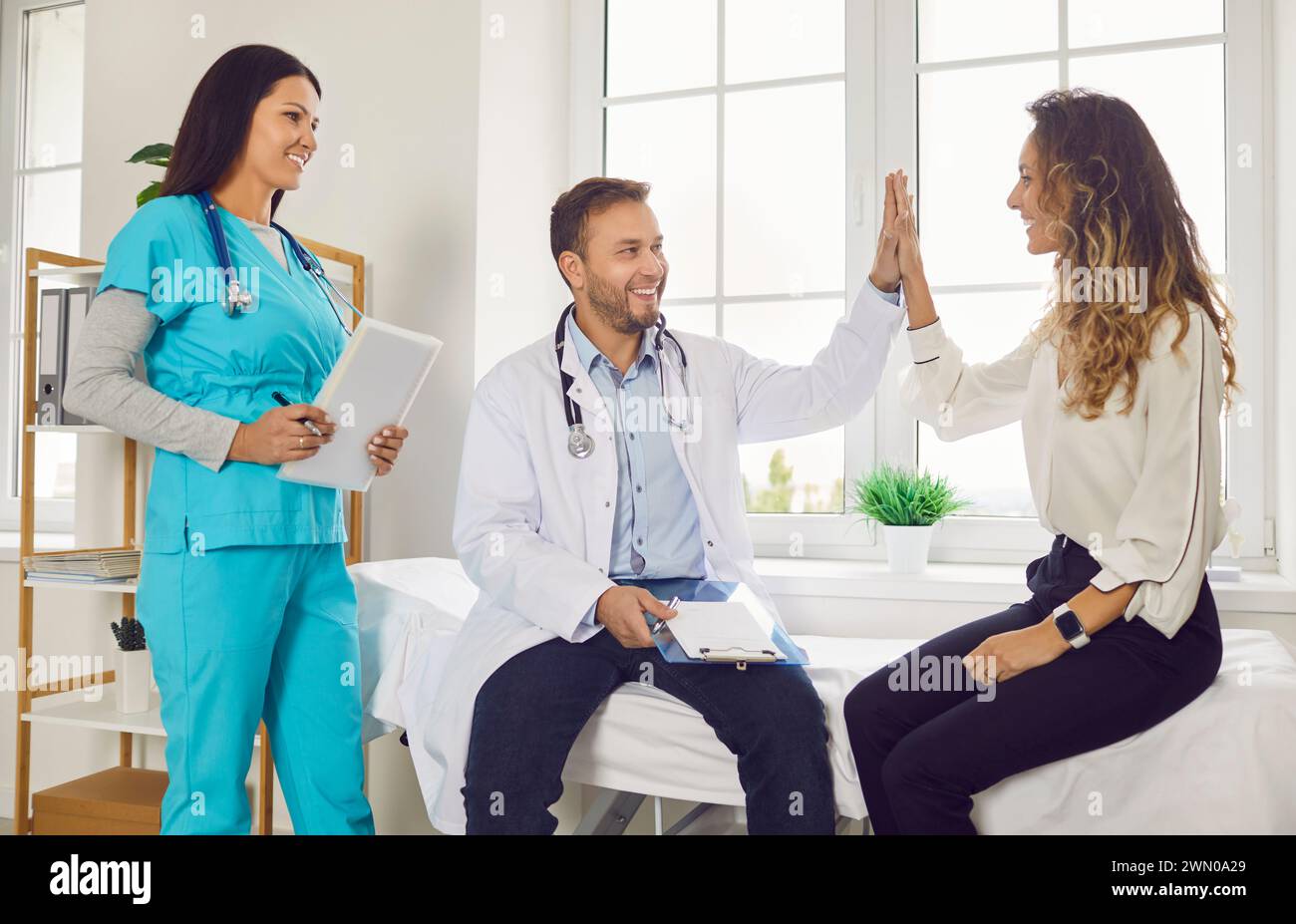 Doctor giving high five with a young happy woman patient in medical ...