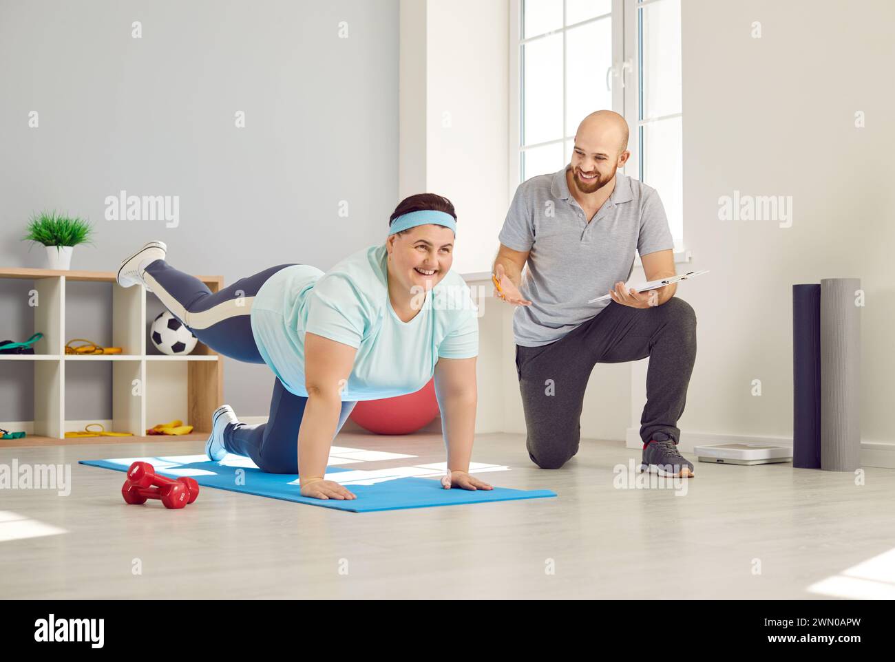 Happy overweight woman doing plank with leg raise during her sports ...