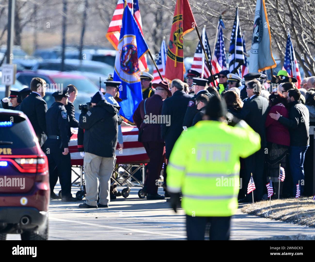 Police officers render a salute as a casket is wheeled into a memorial ...