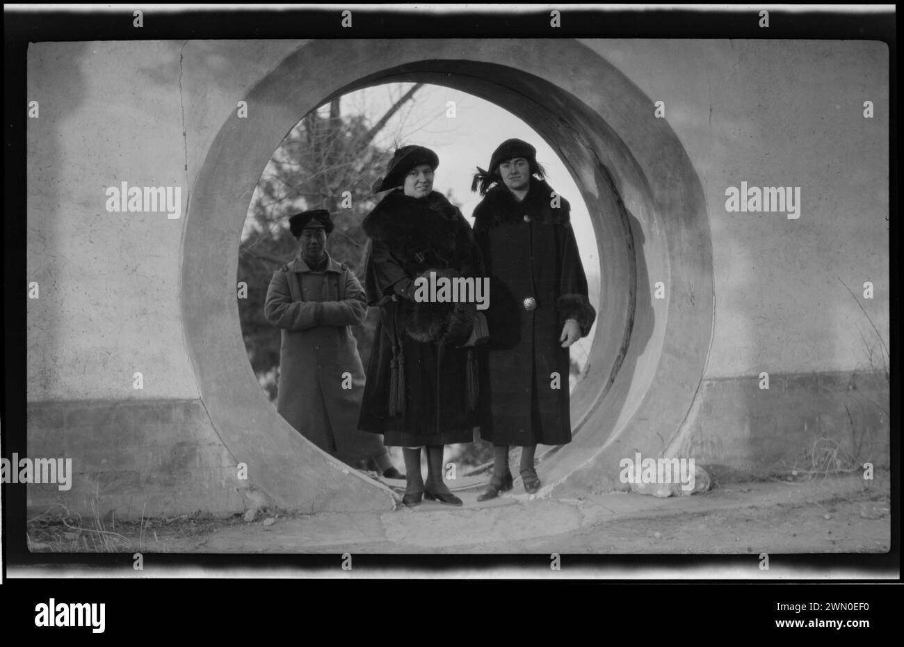 Two women in a circular opening, with someone in the background. Two ...