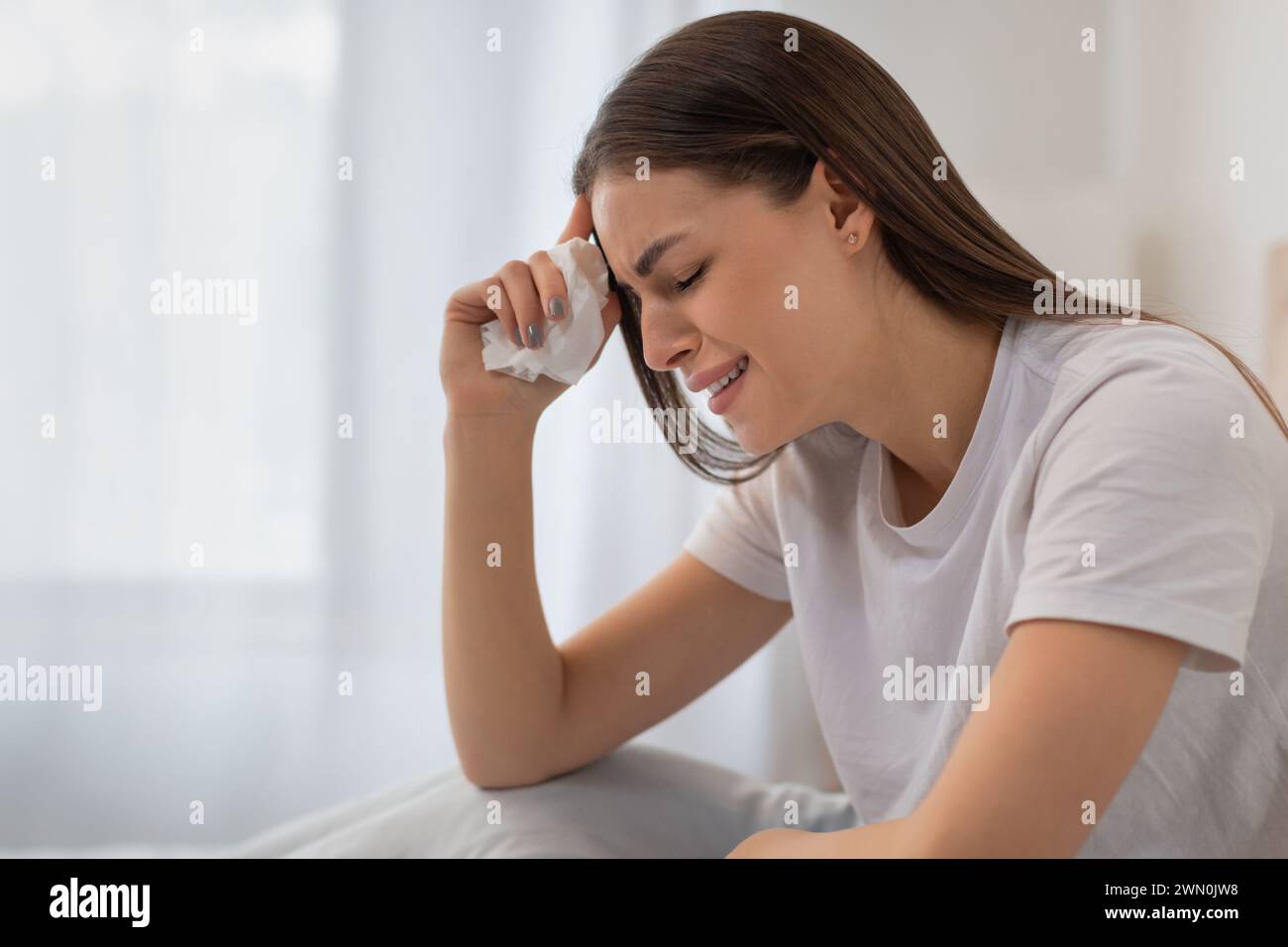 Upset young woman crying and wiping tears with tissue Stock Photo - Alamy