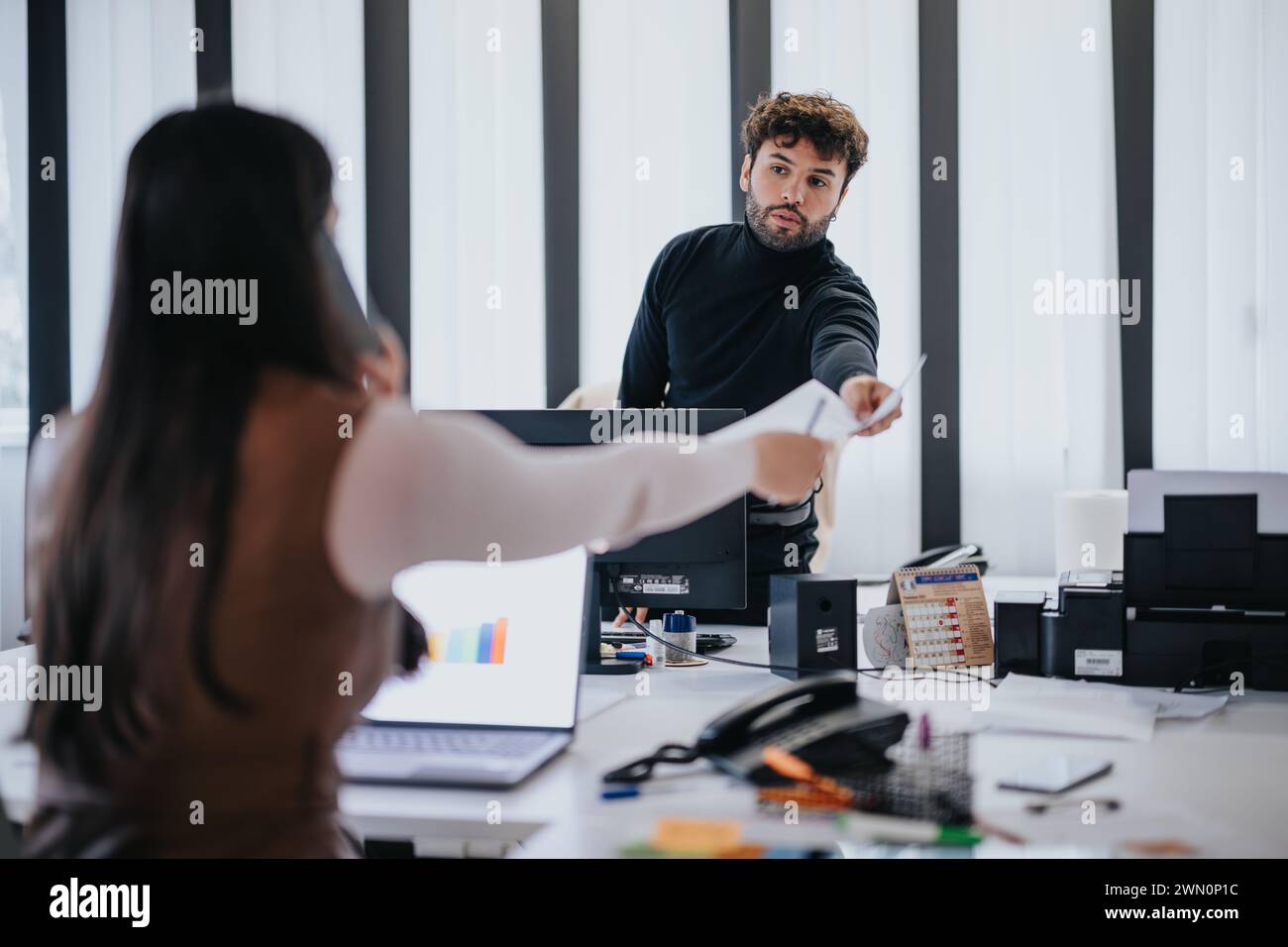 Focused business colleagues exchanging documents in a modern office ...