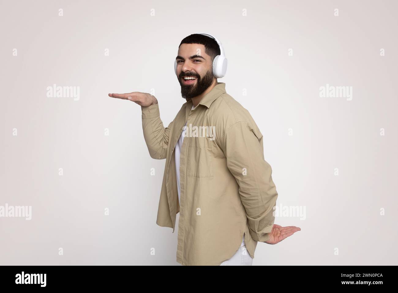 Exuberant bearded man with a wide grin, wearing white headphones and a ...