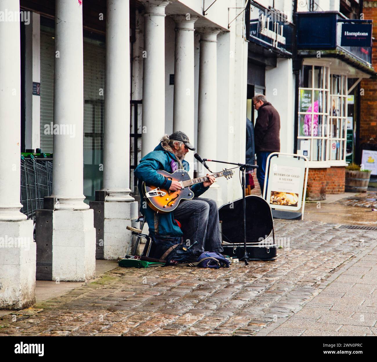 A street busker/performer with a guitar on the high street in the ...