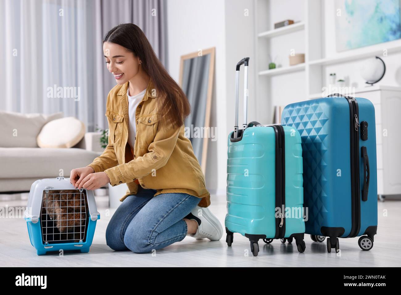 Smiling woman closing carrier with her pet before travelling indoors ...