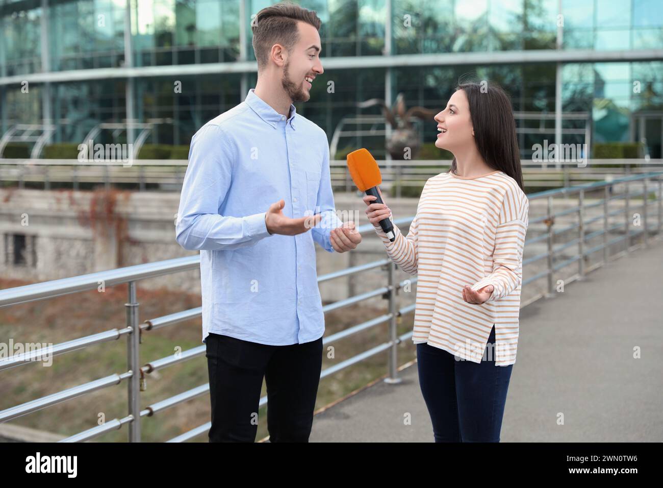 Young journalist interviewing man on city street Stock Photo - Alamy