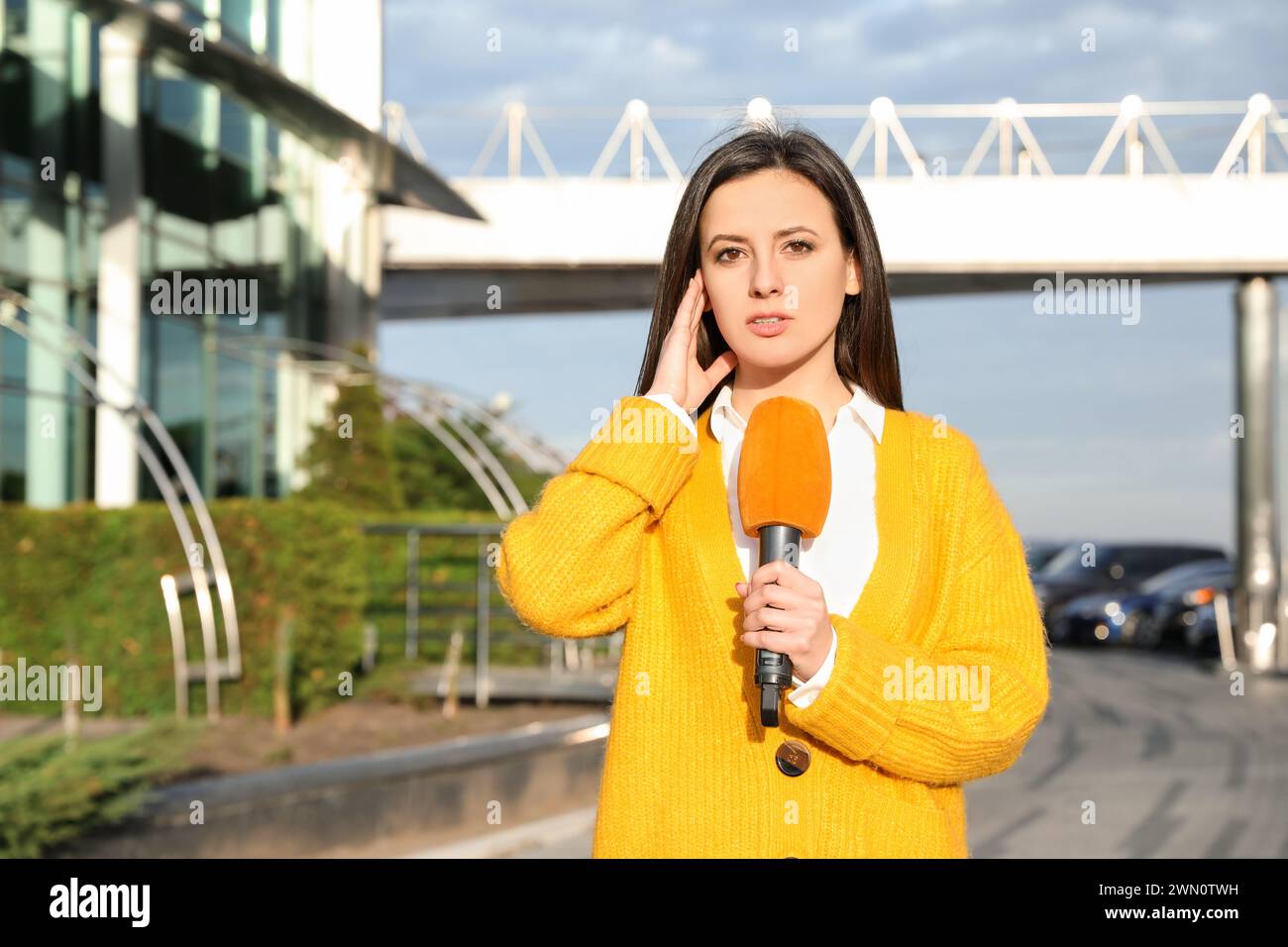 Young female journalist with microphone working on city street Stock ...