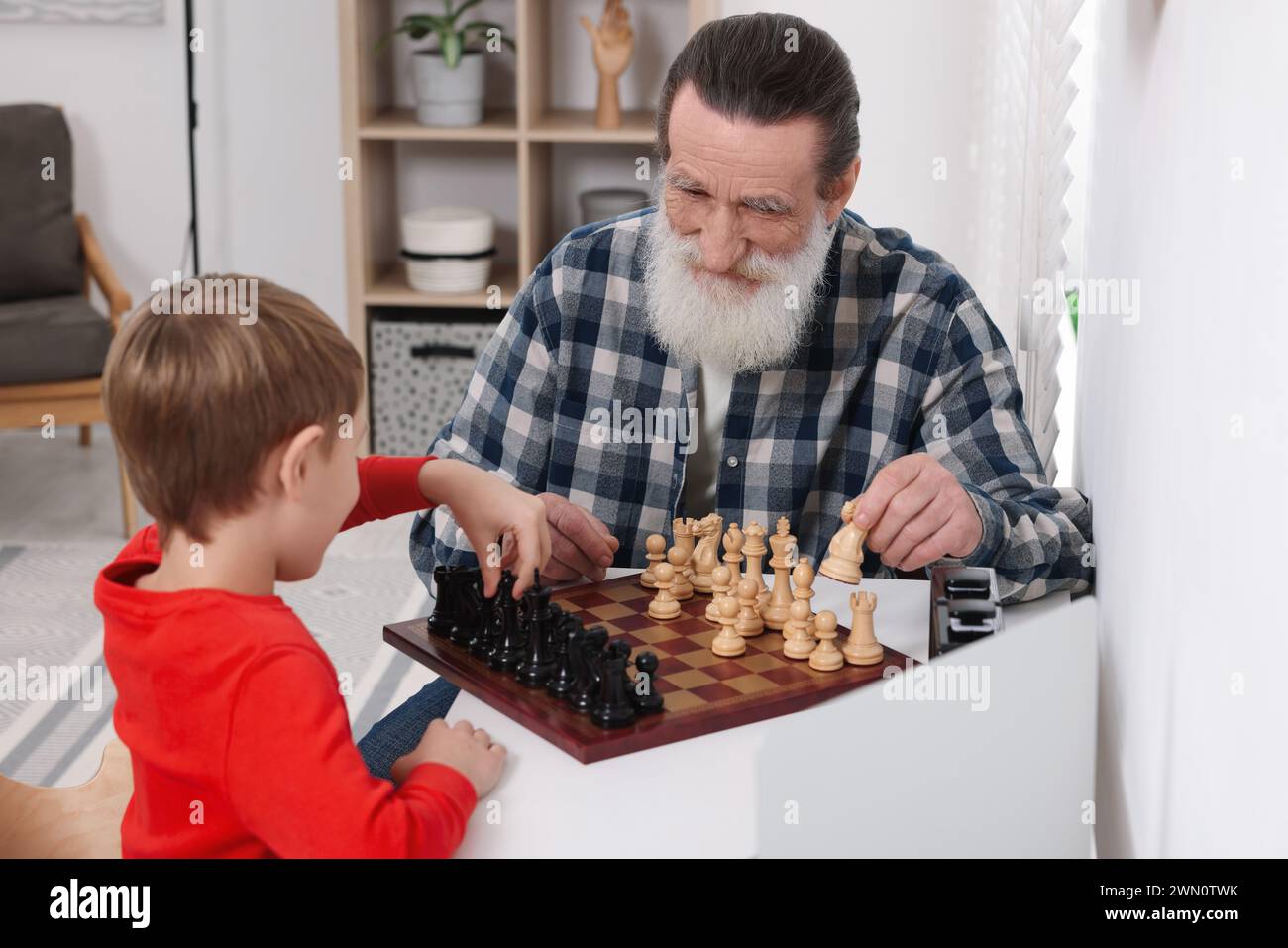 Grandfather and grandson playing chess at table in room Stock Photo - Alamy