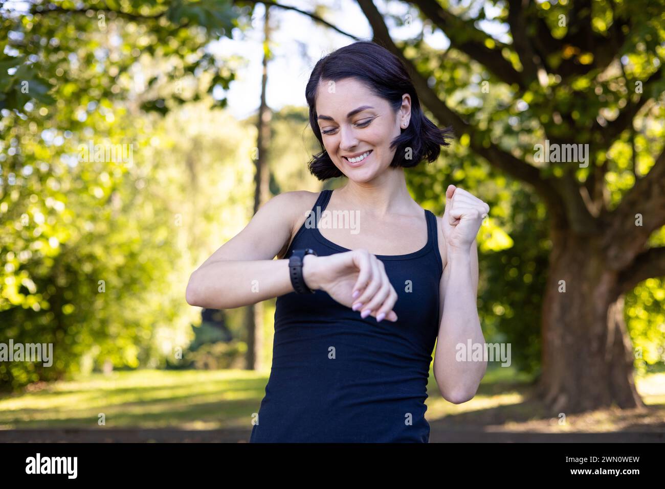 Joyful female runner checking her smartwatch, monitoring performance ...