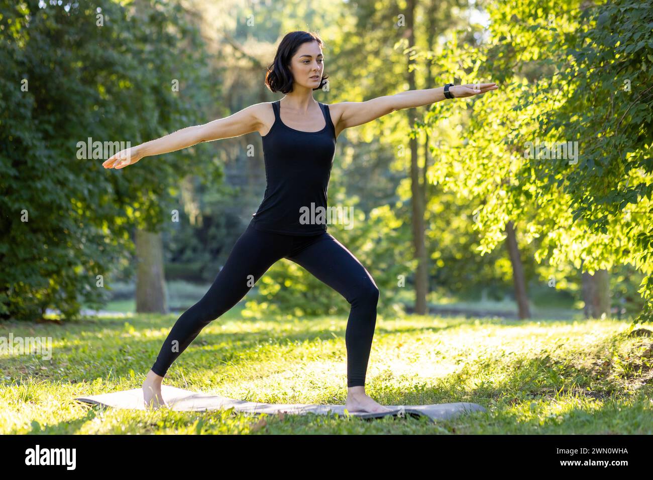 Focused woman engaging in a yoga practice in a peaceful park, with ...