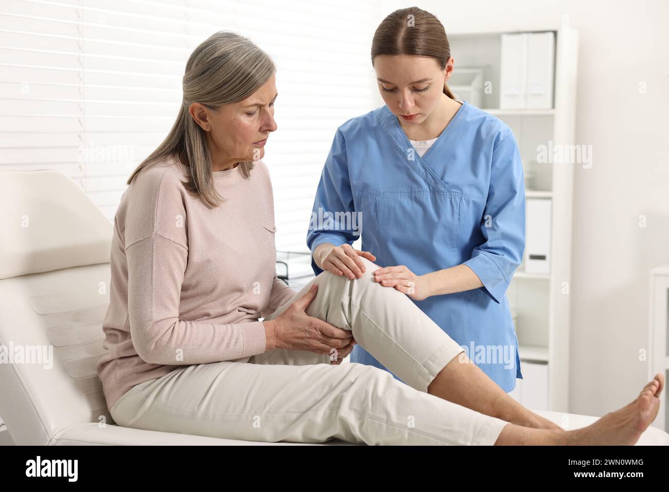 Arthritis symptoms. Doctor examining patient with knee pain in hospital ...