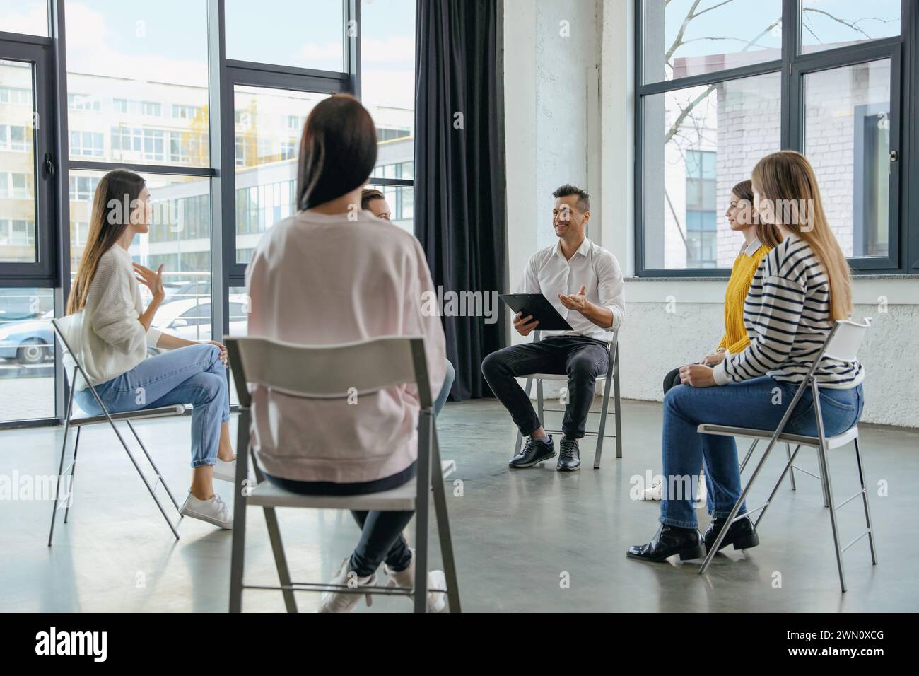 Psychotherapist working with patients in group therapy session indoors ...