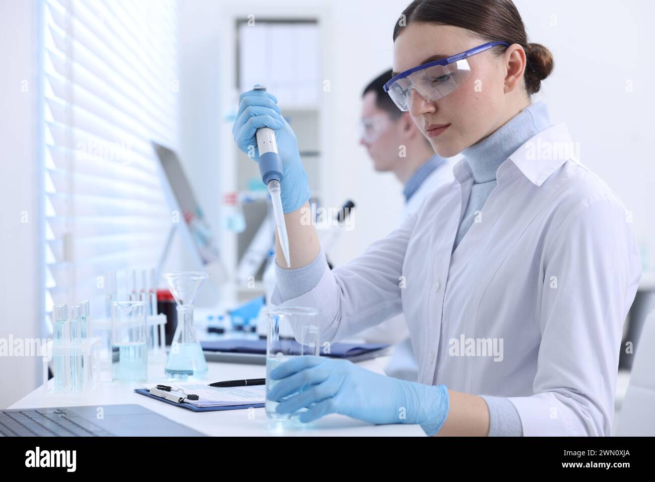 Scientist dripping sample into beaker in laboratory Stock Photo - Alamy