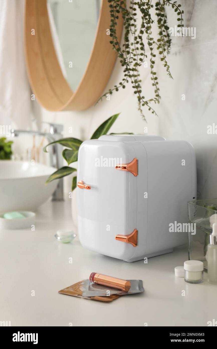 Cosmetics refrigerator and skin care products on white countertop in ...