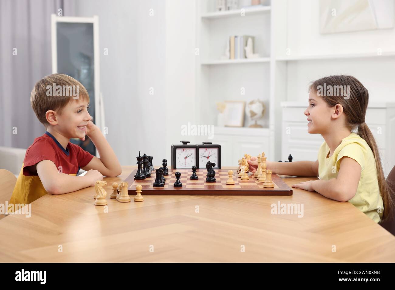 Cute children playing chess at table in room Stock Photo - Alamy