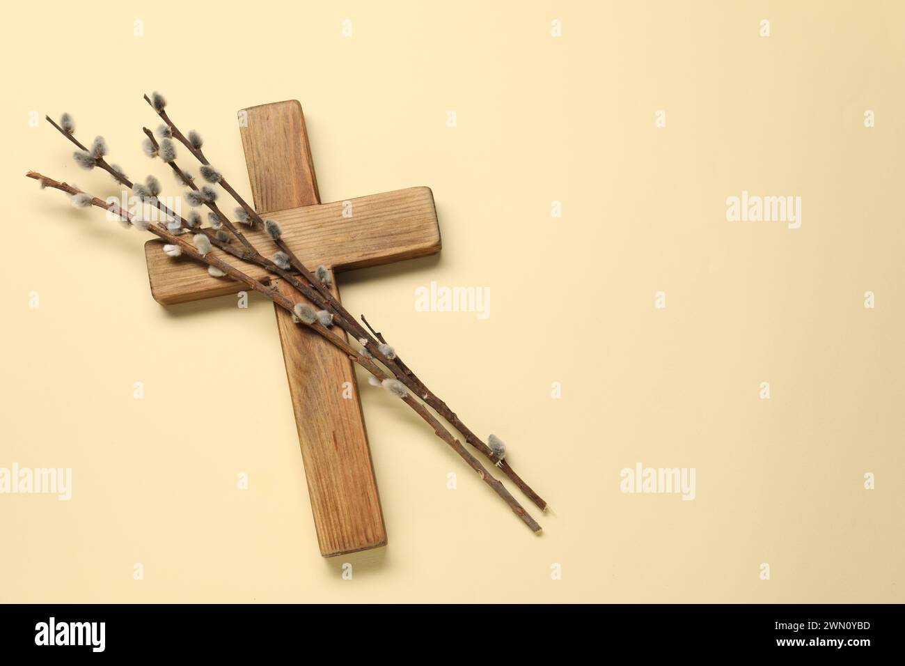 Wooden cross and willow branches on beige background, top view with ...