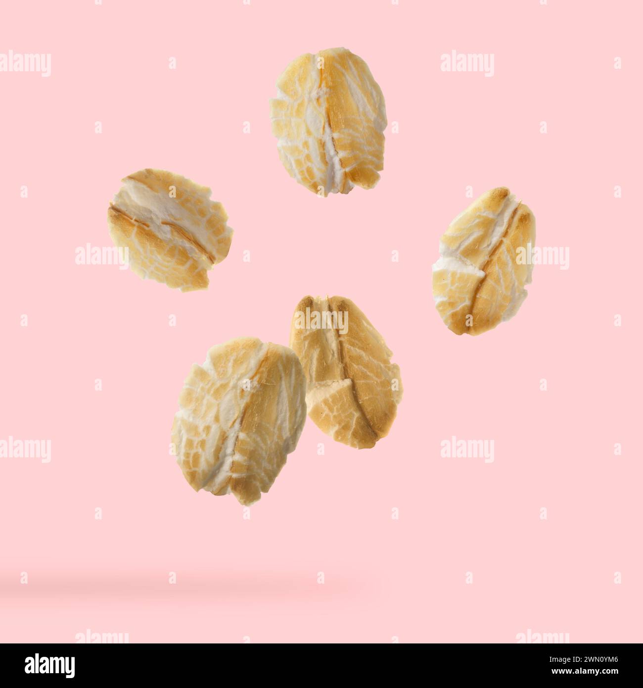 Rolled oat flakes falling on pink background Stock Photo - Alamy