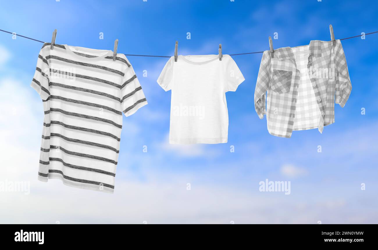 Different clothes drying on washing line against blue sky, banner ...