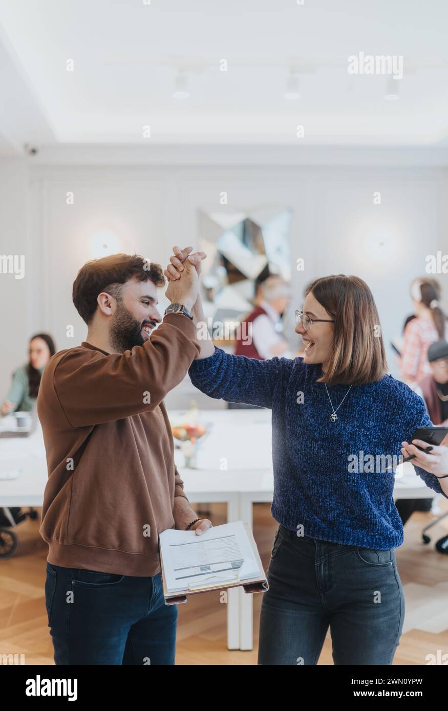 Team success celebration. Two, young colleagues high-fiving in a bright ...
