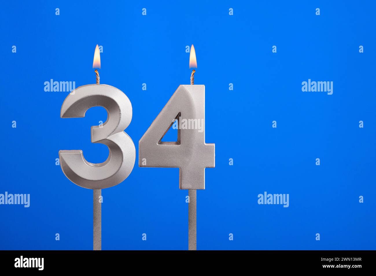 Birthday number 34 - Candle lit on blue background Stock Photo - Alamy