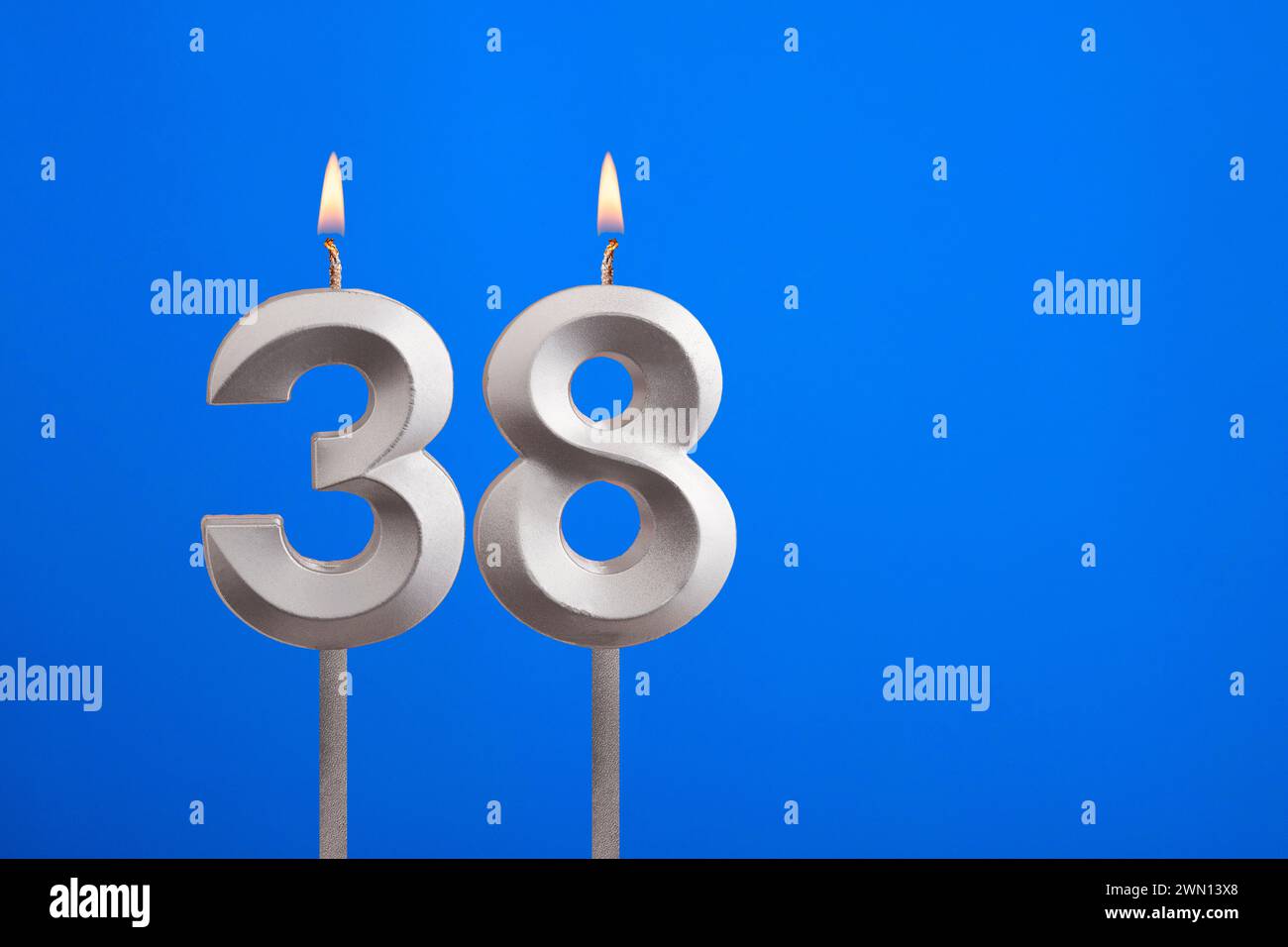 Birthday number 38 - Candle lit on blue background Stock Photo - Alamy