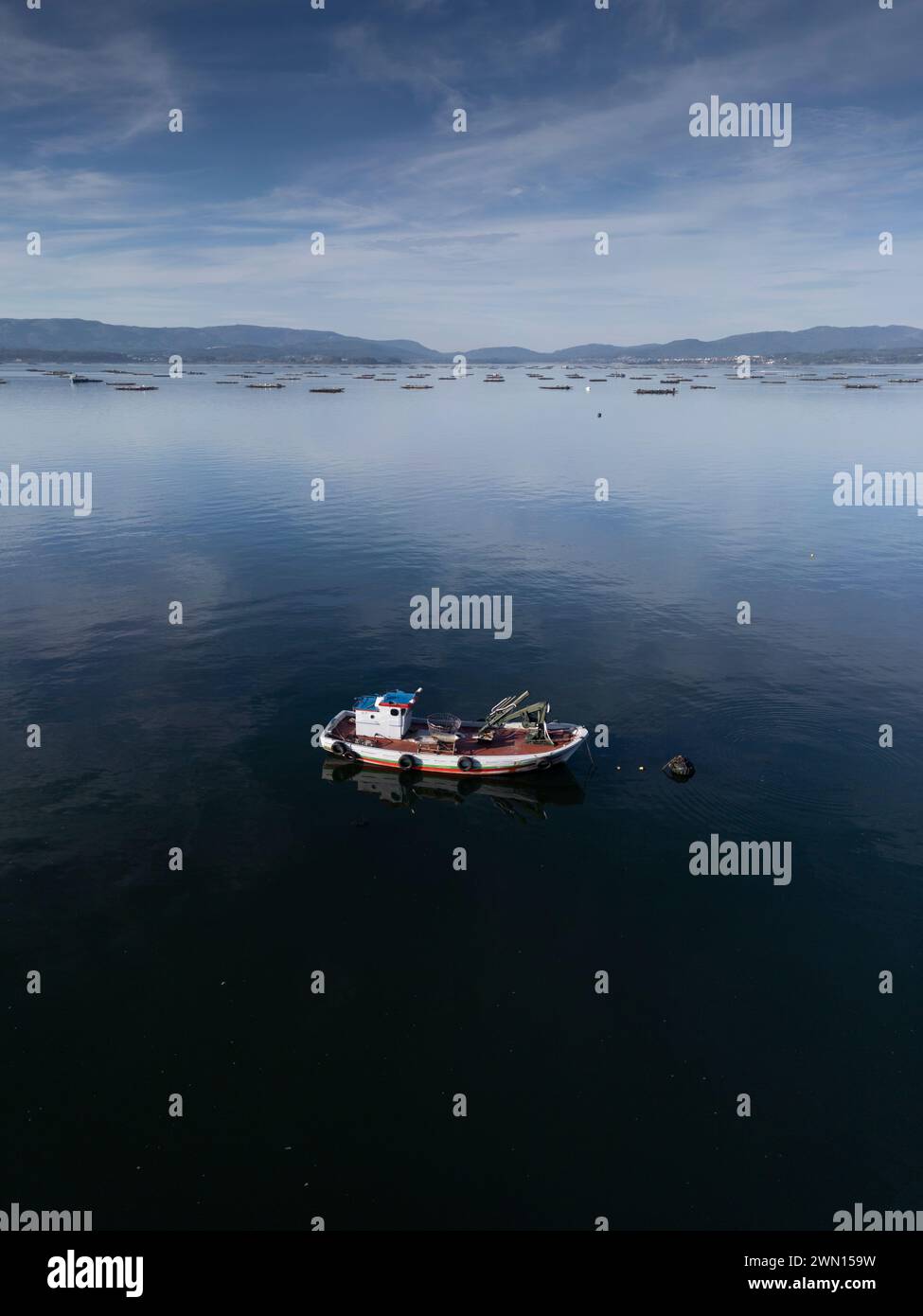 A small wooden fishing boat anchored in the Arousa estuary. Mussel ...