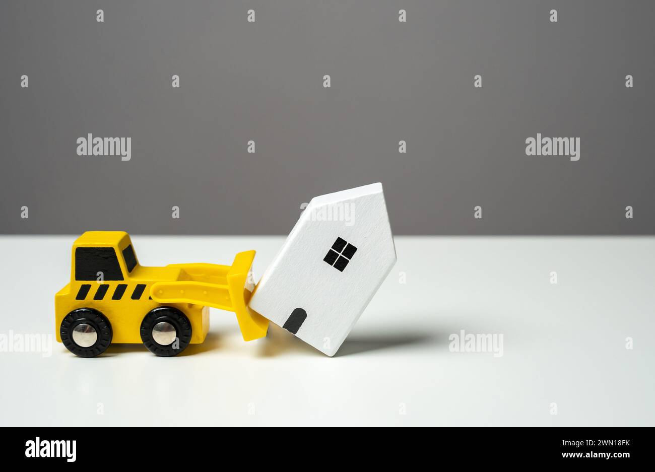 A bulldozer demolishes a house. Toy figures. Territory clearing service ...