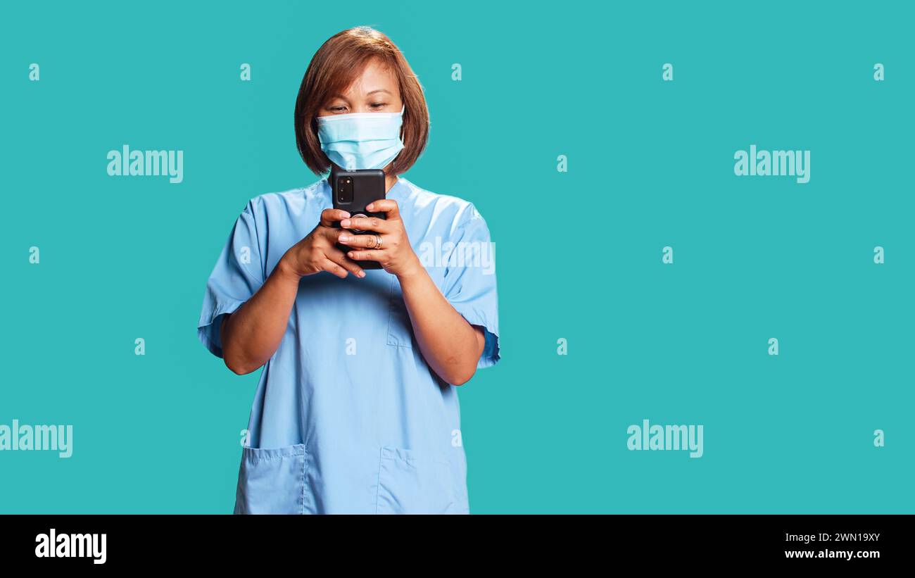 Happy relaxed nurse chatting with friends online while taking hospital ...