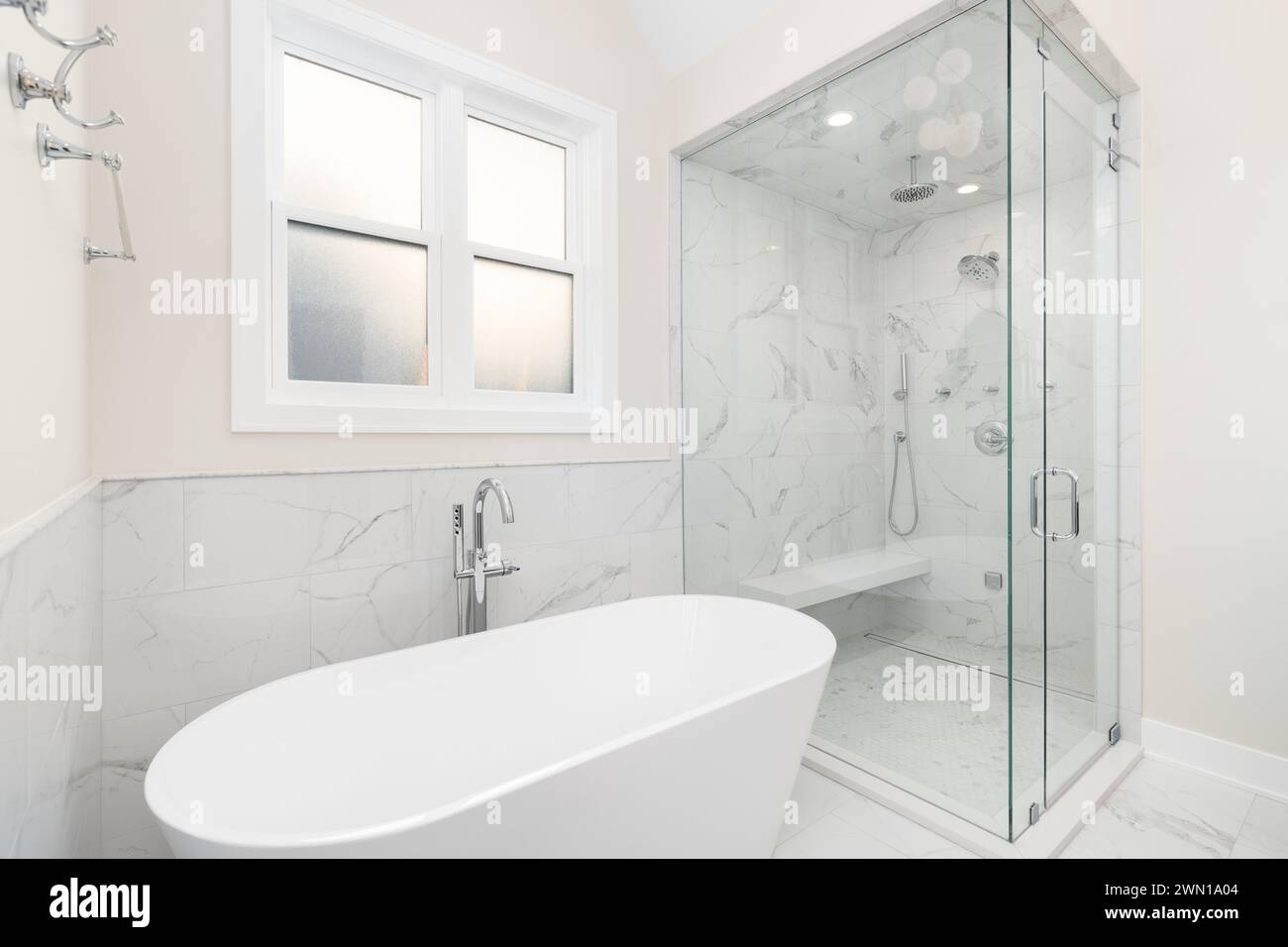 A bathroom's freestanding bathtub with a chrome faucet, marble tile on ...