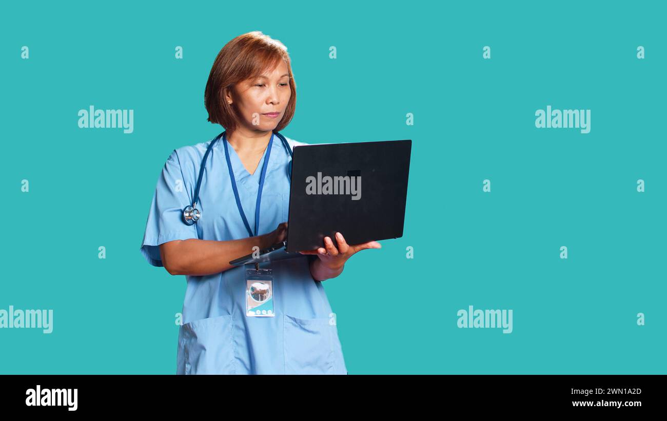 Focused asian nurse typing patient data on laptop after finishing ...