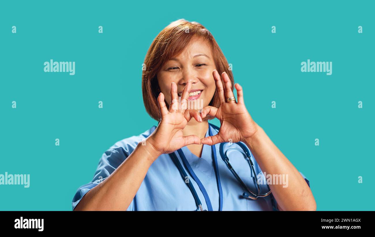 Close up shot of joyful qualified BIPOC nurse doing heart symbol shape ...