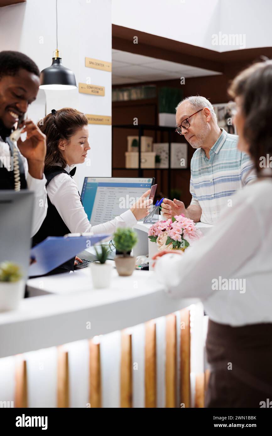 Retired senior tourists arrives at hotel reception, assisted by ...