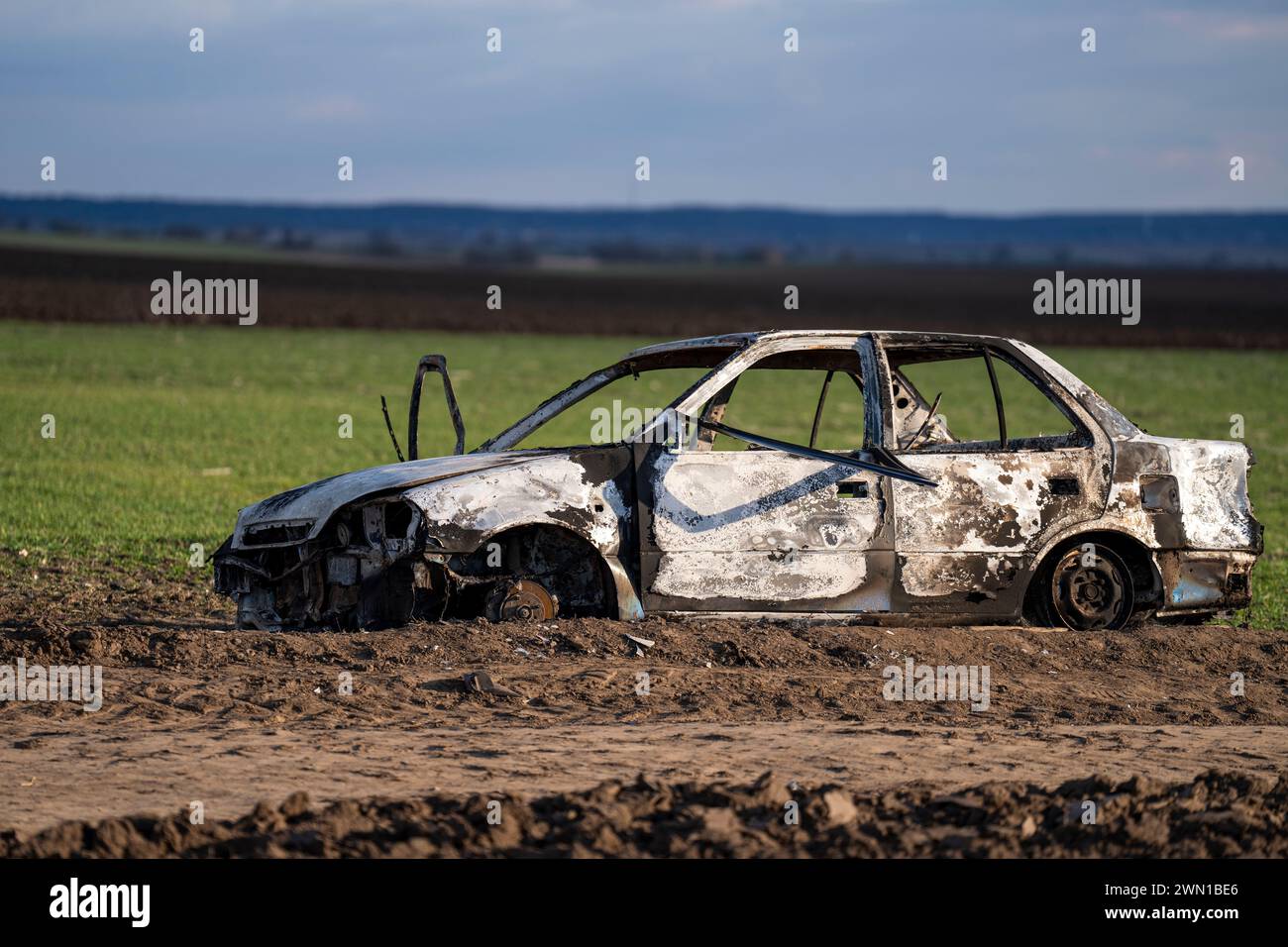 A burned out car. Burnt car in the field. Car fire, vehicle fire due to ...