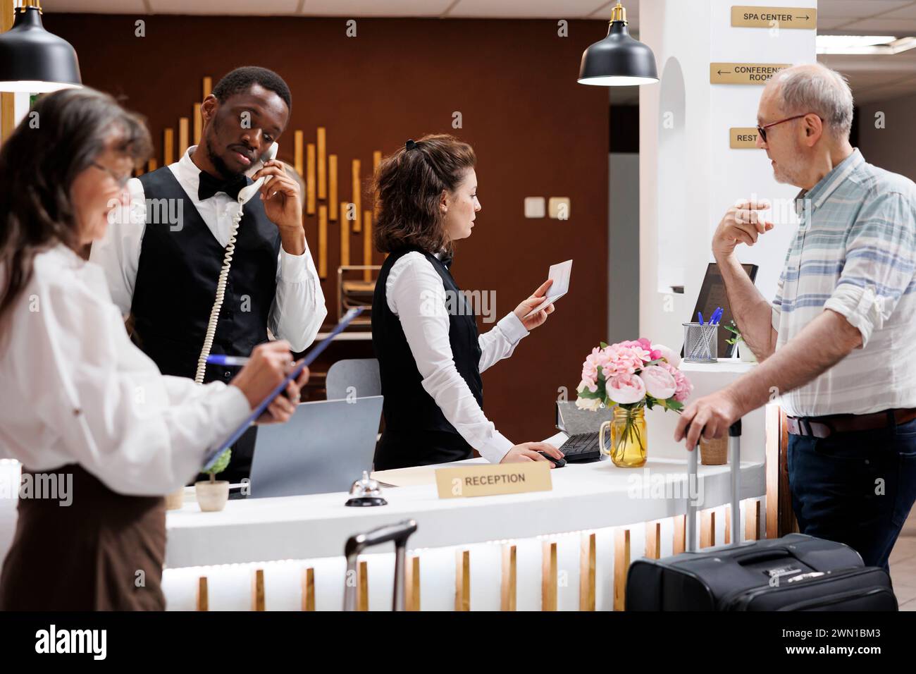 While african american staff answers phone, female concierge verifies ...