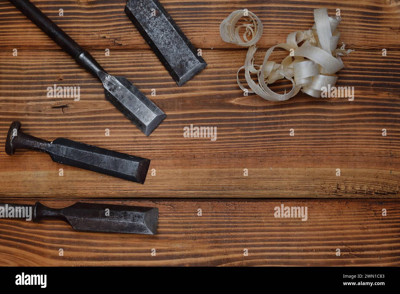 Old bench chisels and wood shaving on a burnt wood surface. Woodworking ...