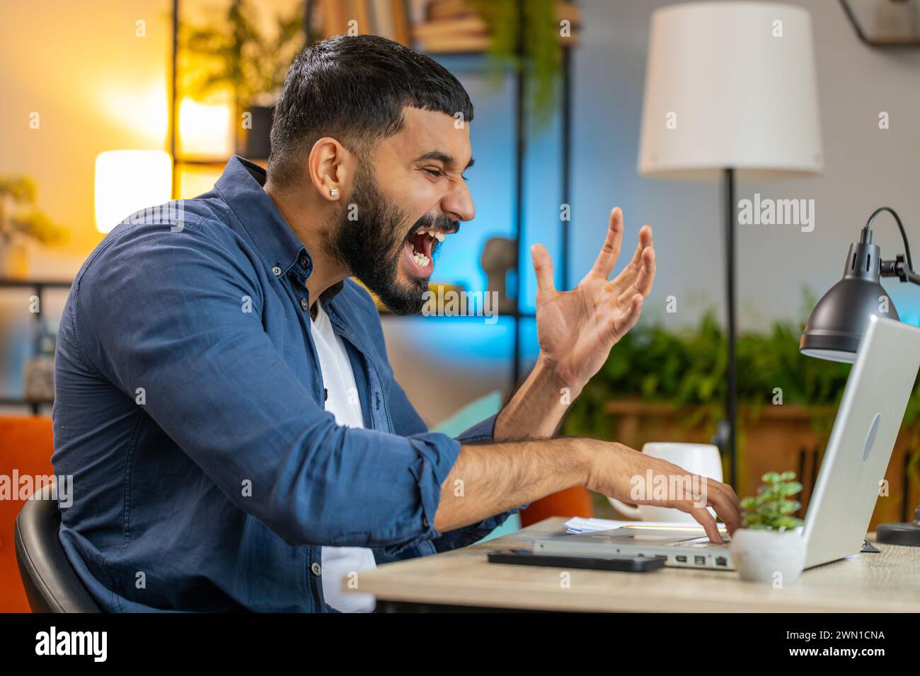 Angry furious Indian man freelancer using laptop while working at home ...
