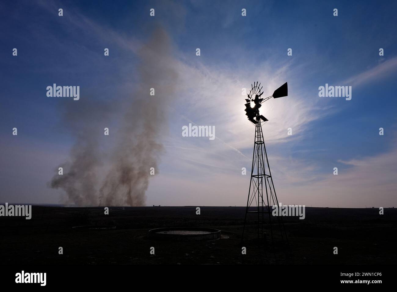 Smoke billows on a field near a windmill during the Smokehouse Creek ...