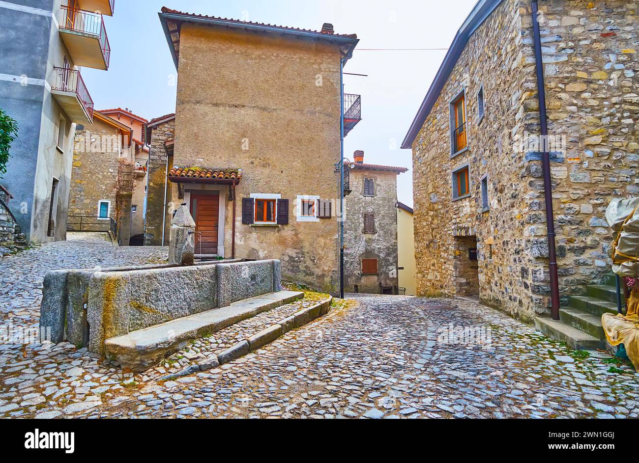 The narrow street in Bre with stone houses and drinking fountain ...