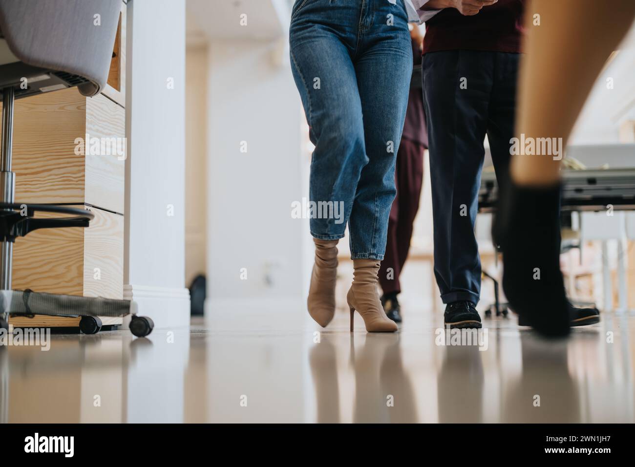 Low angle view of coworkers casually walking in the office, reflecting ...