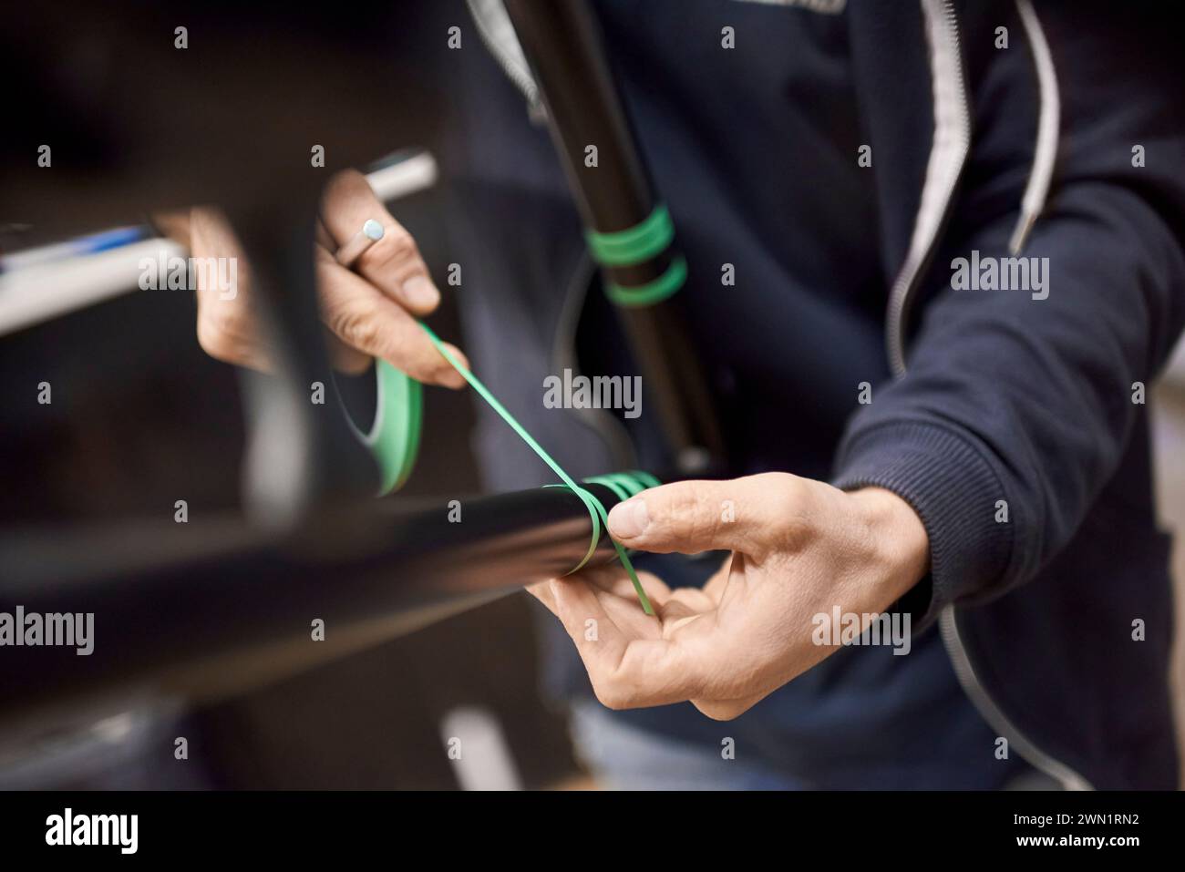 Worker hands, unrecognizable man preparing a bicycle frame with masking ...