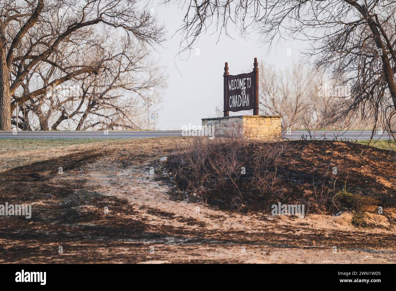 A "WELCOME TO CANADIAN" sign stands amidst grass burnt by the ...