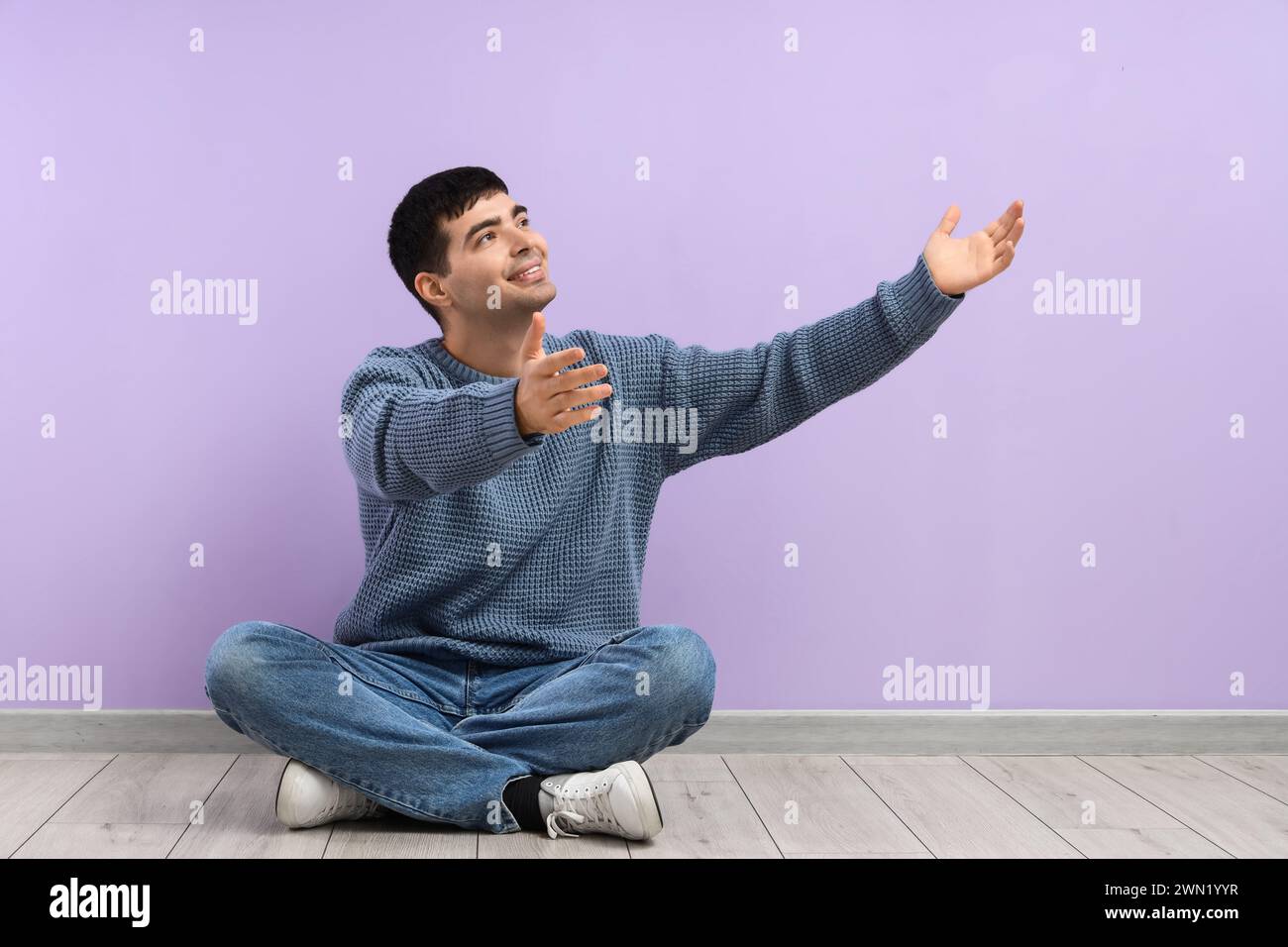 Young man opening arms for hug near lilac wall Stock Photo - Alamy
