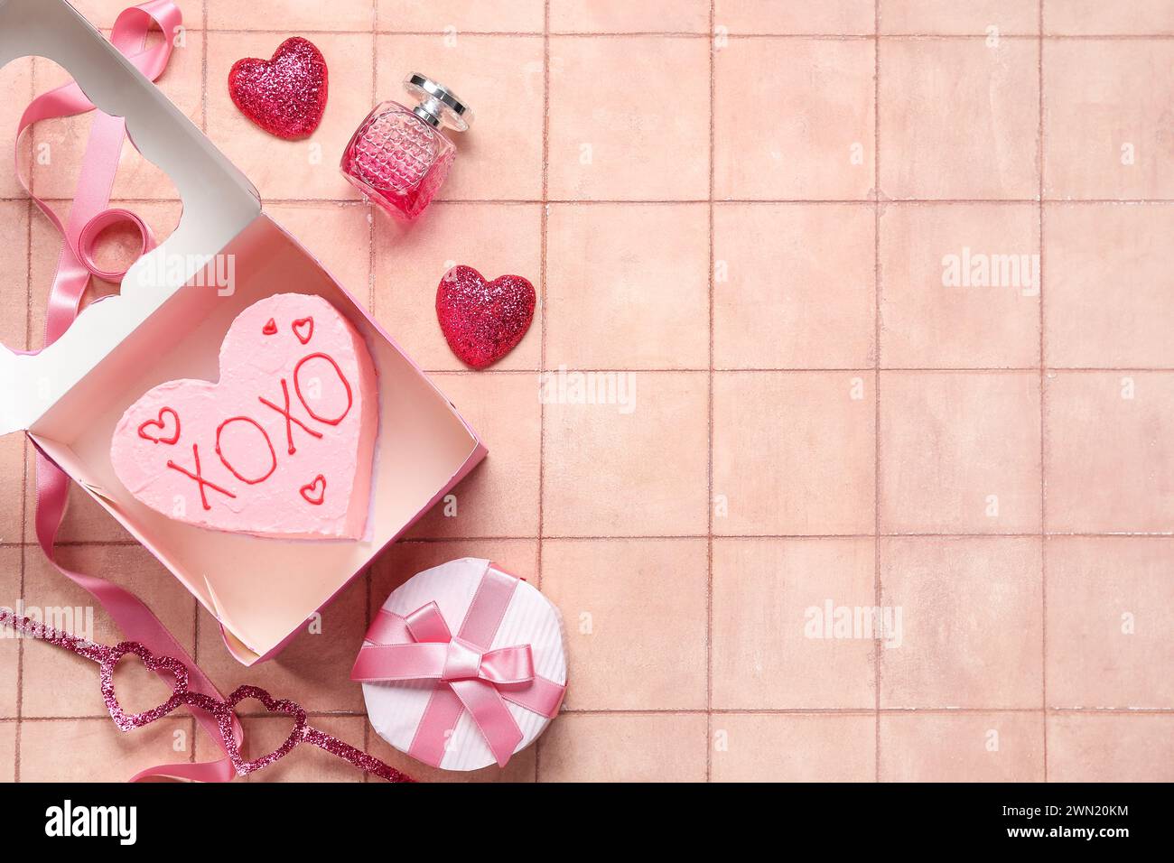 Heart-shaped bento cake with gift box and perfume on pink tile ...