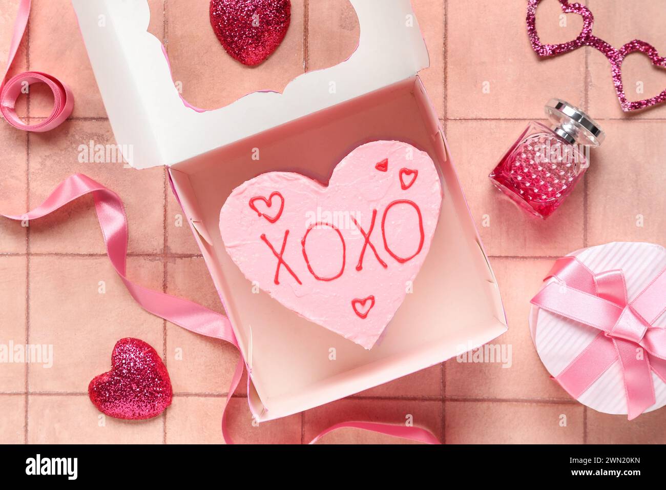 Heart-shaped bento cake with gift box and perfume on pink tile ...